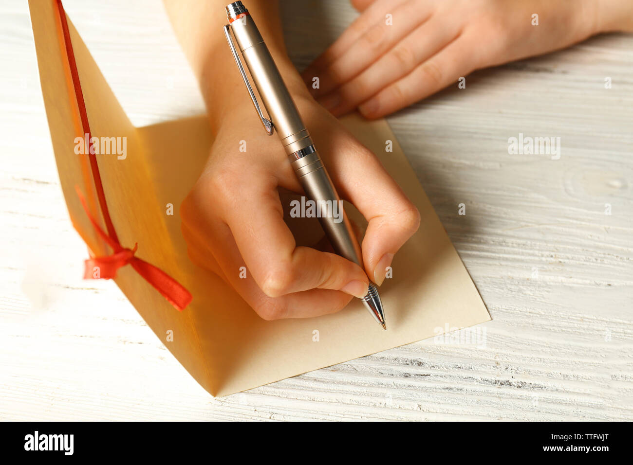 Female hands signing gift card for Valentine's Day on white wooden ...