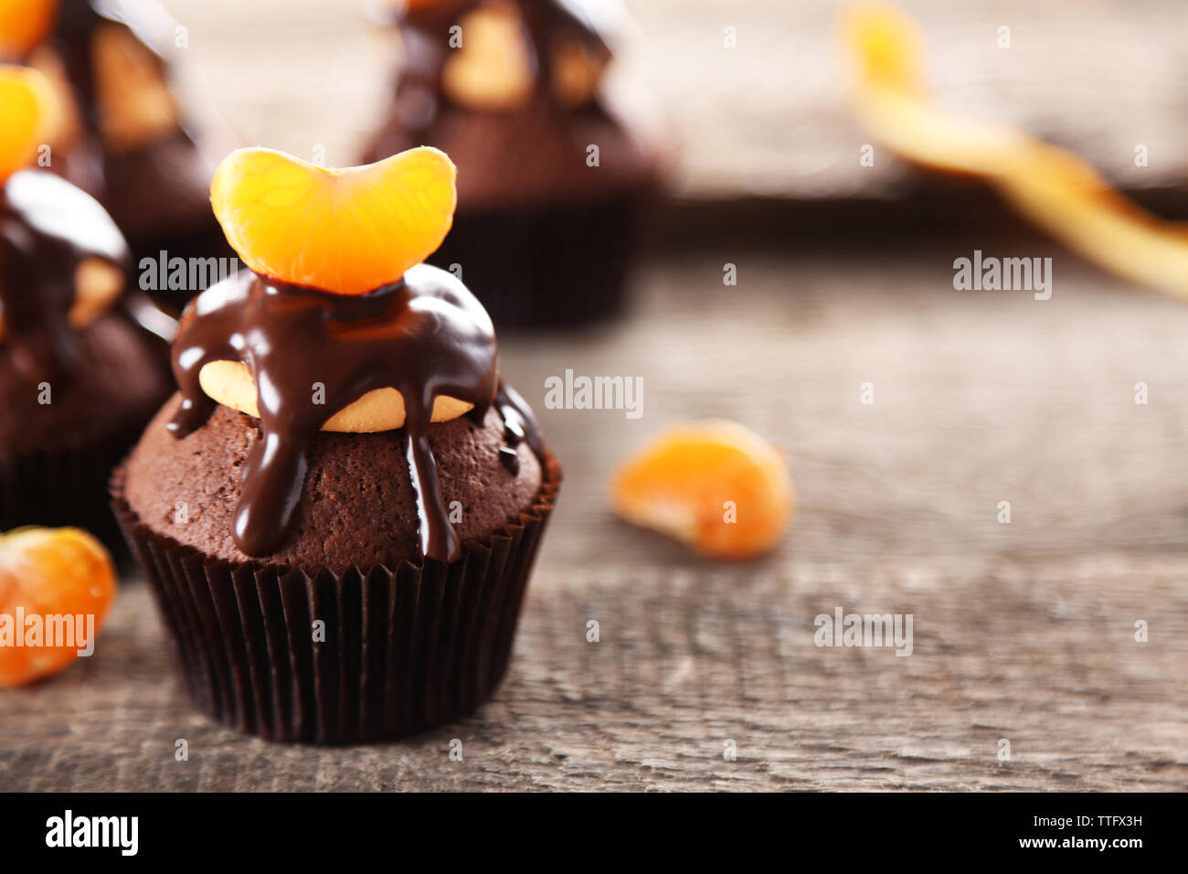 Tasty cupcakes with slice of mandarin and chocolate on wooden ...