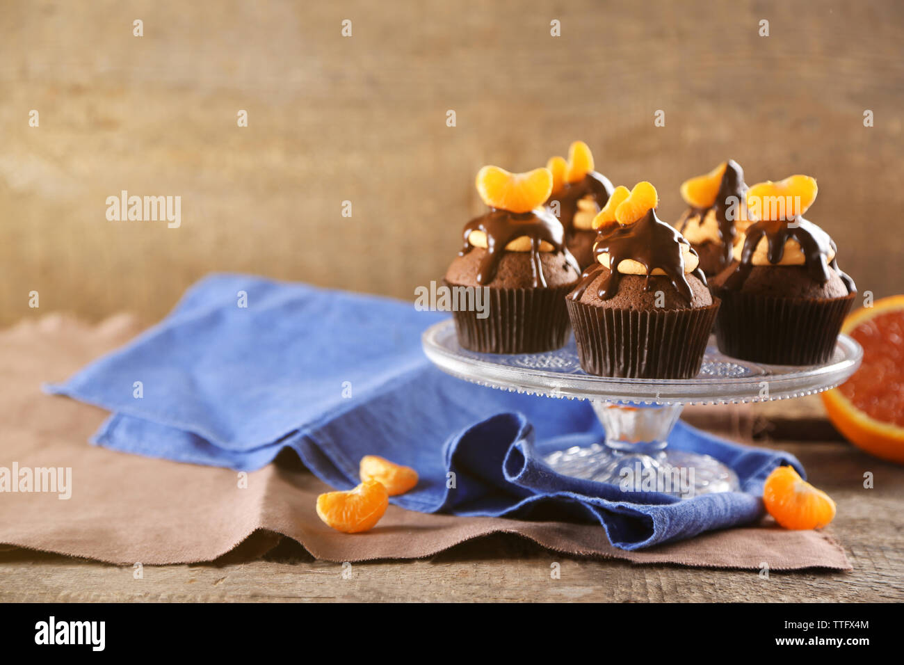 Tasty cupcakes with slice of mandarin and chocolate on wooden ...