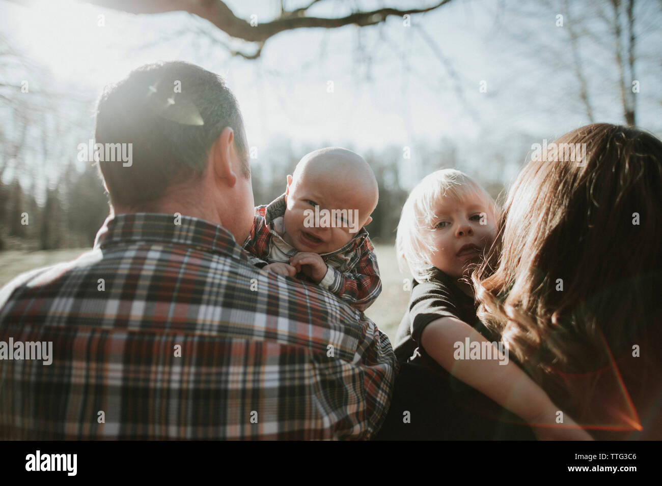 Baby and toddler look over shoulder of their parents Stock Photo - Alamy