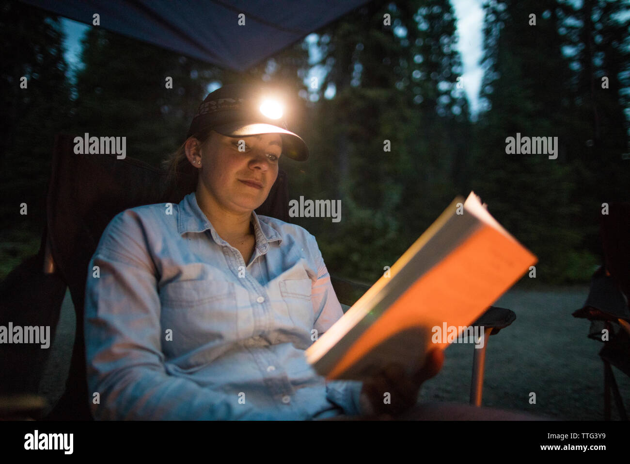 Woman reading book with headlamp outdoors while camping Stock Photo - Alamy