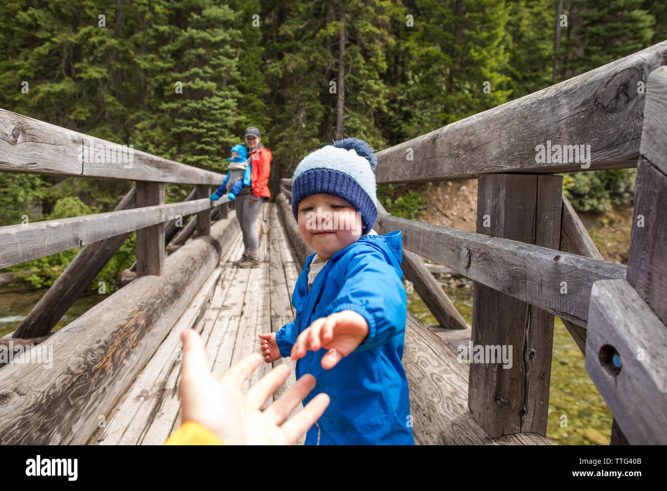 Toddler boy reaching for fathers hand, safely cross wooden bridge Stock ...