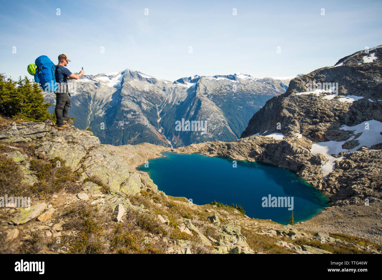 Backpacker photographs a blue tarn, British Columbia Stock Photo - Alamy