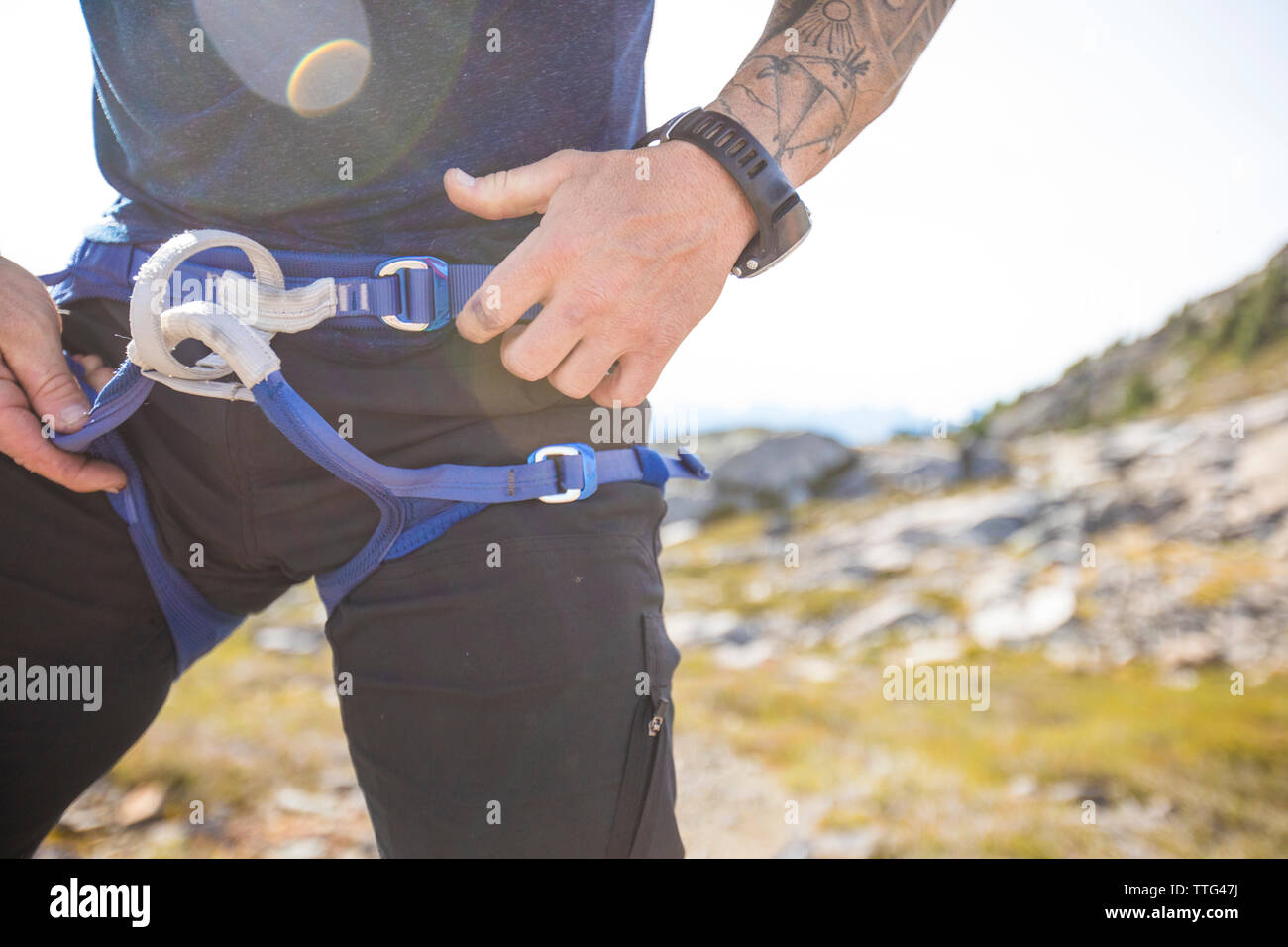 A climber checks his harness prior to beginning a rock climbing route ...