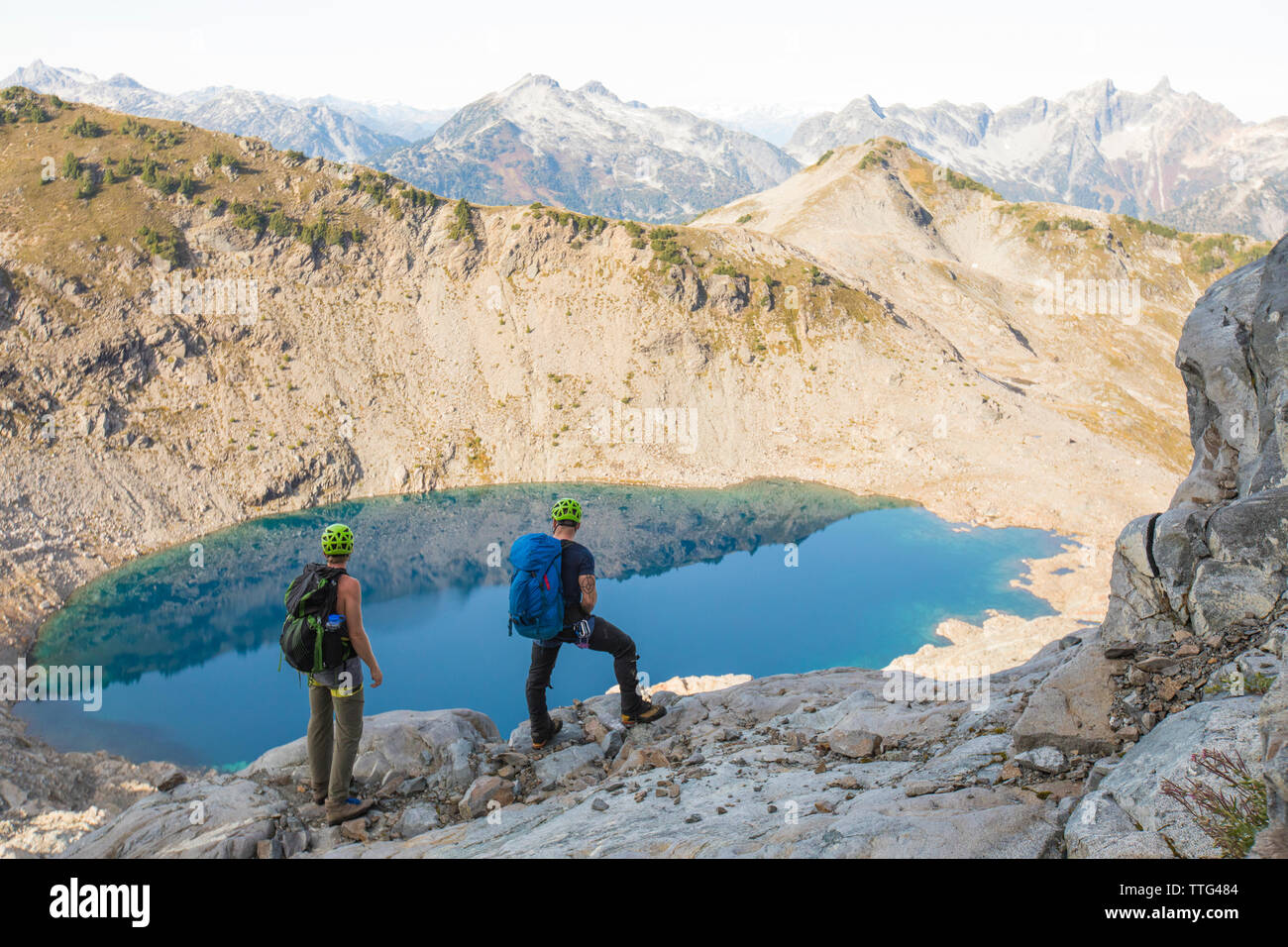 Mountaineers look down on alpine tarn and surrounding peaks Stock Photo ...