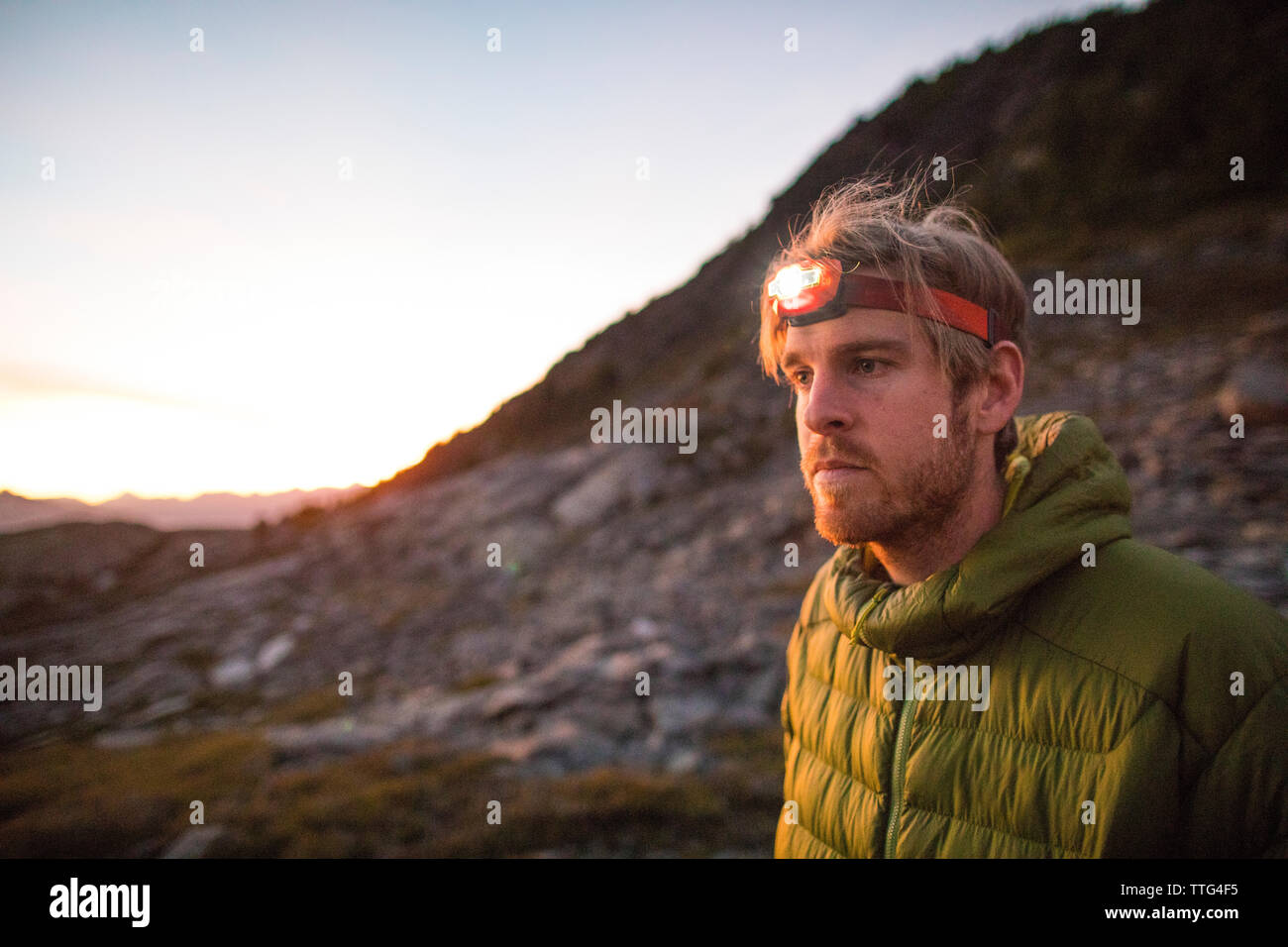 Portrait of man wearing headlamp at dusk in the mountains Stock Photo ...