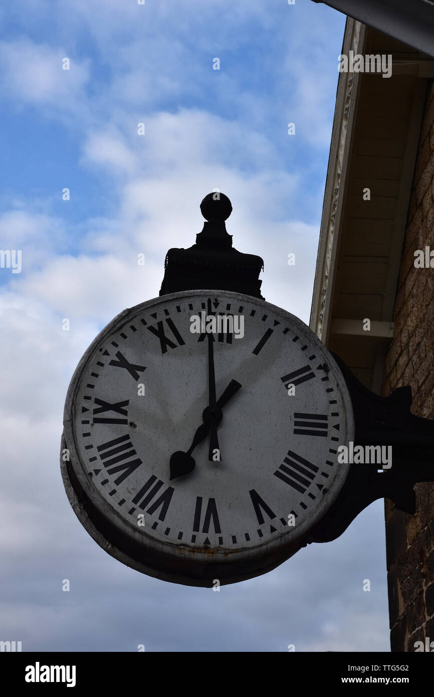 Old fashioned train station clock suspended above the train tracks ...