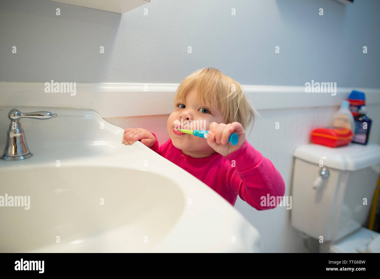 Portrait of girl brushing teeth by bathroom sink at home Stock Photo ...