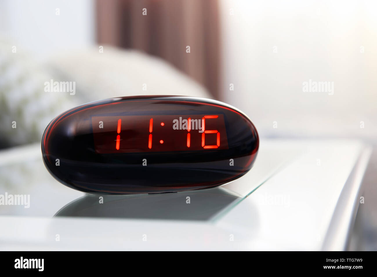 Digital clock on a bedside table in bedroom Stock Photo - Alamy