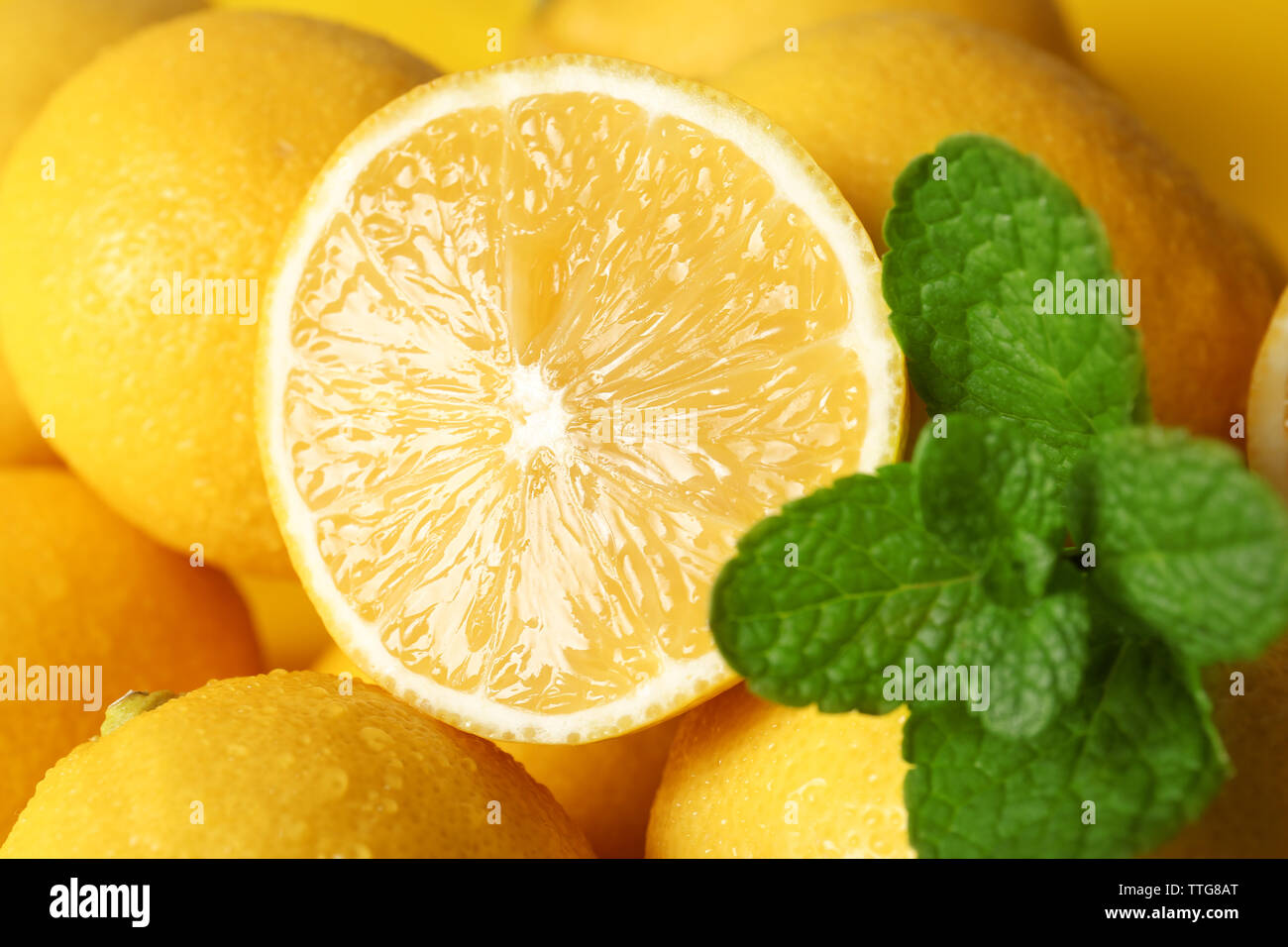 Pile of wet lemons with halves and green leaves closeup Stock Photo - Alamy