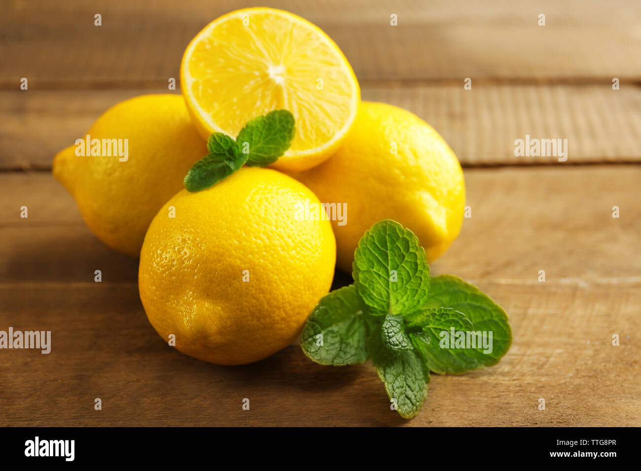Sliced fresh lemons with green leaves on wooden background Stock Photo ...