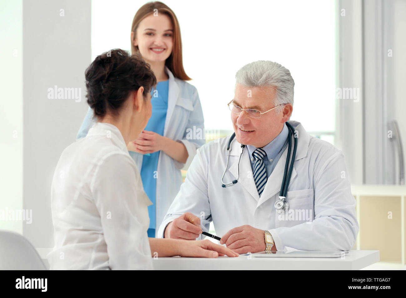 Doctors and patient in office Stock Photo - Alamy
