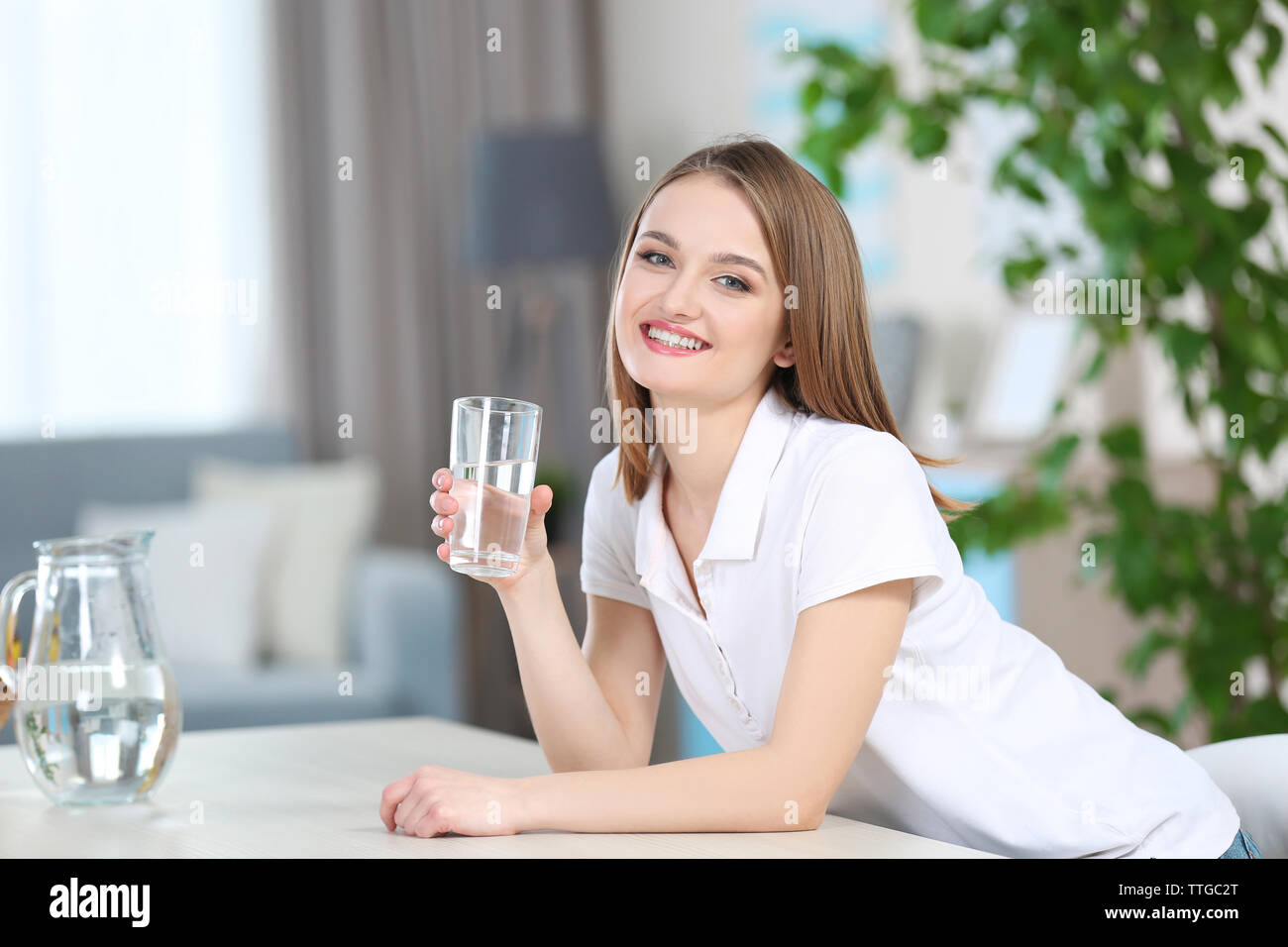 Young woman drinking water from glass in the kitchen Stock Photo - Alamy