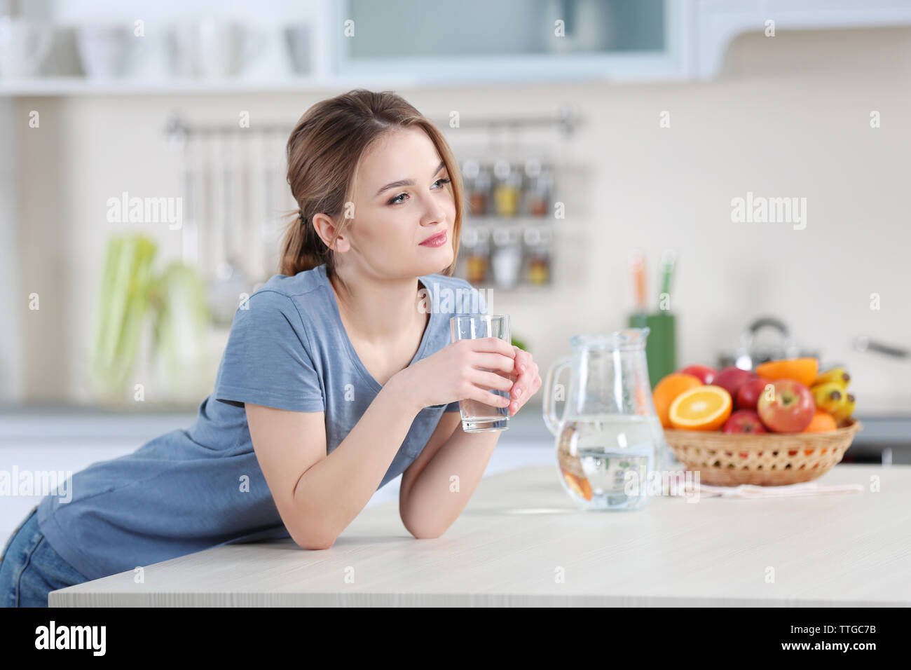 Young woman drinking water from glass in the kitchen Stock Photo - Alamy