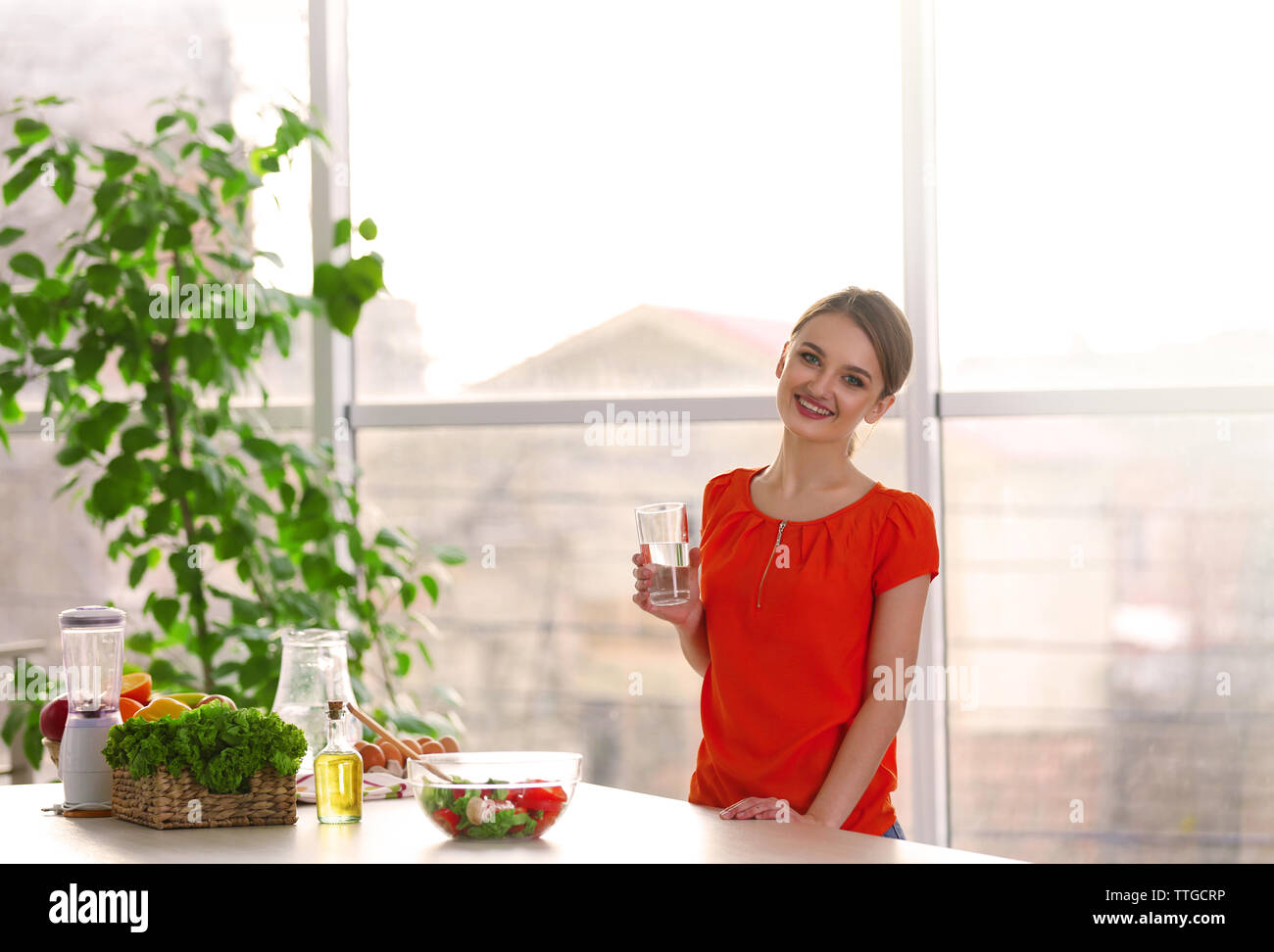 Young woman drinking water near table with fruits and vegetables in the kitchen Stock Photo - Alamy