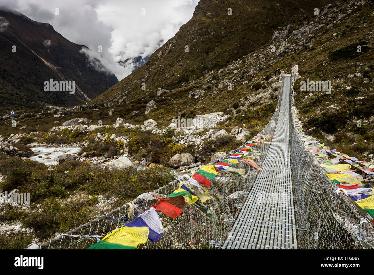 Mountain valley with prayer flag lined swing bridge Stock Photo - Alamy