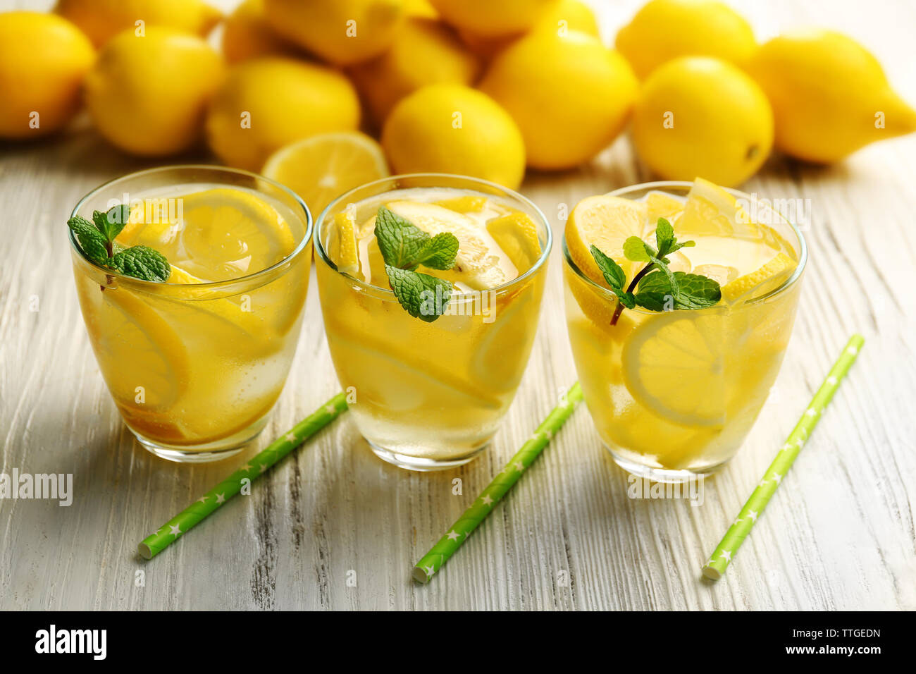 Row of lemonades with lemons and mint on white wooden table background ...