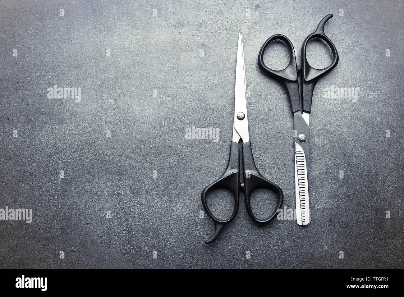 Professional scissors with black handles on a dark grey surface, top ...