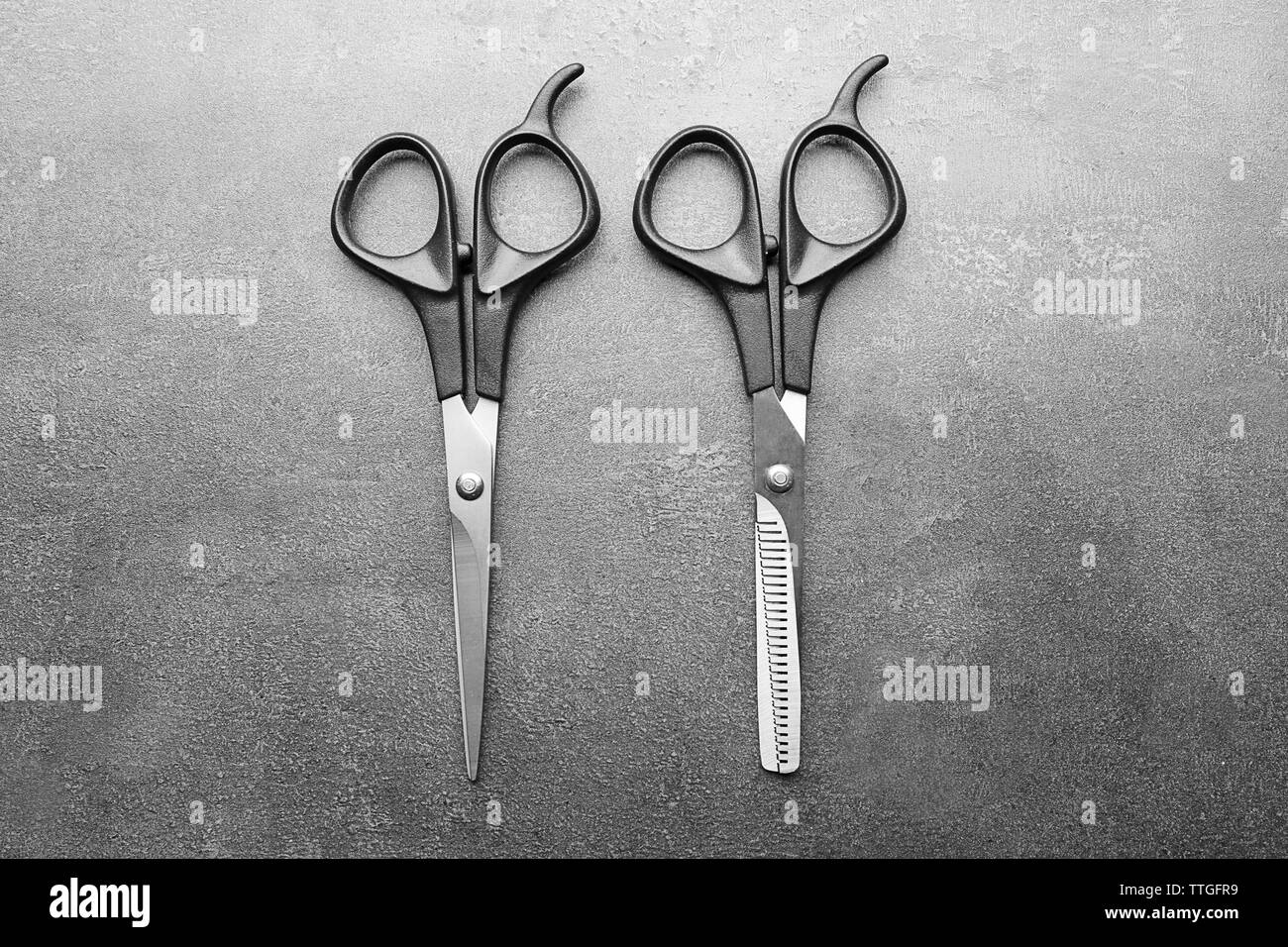 Professional scissors with black handles on a dark grey surface, top ...