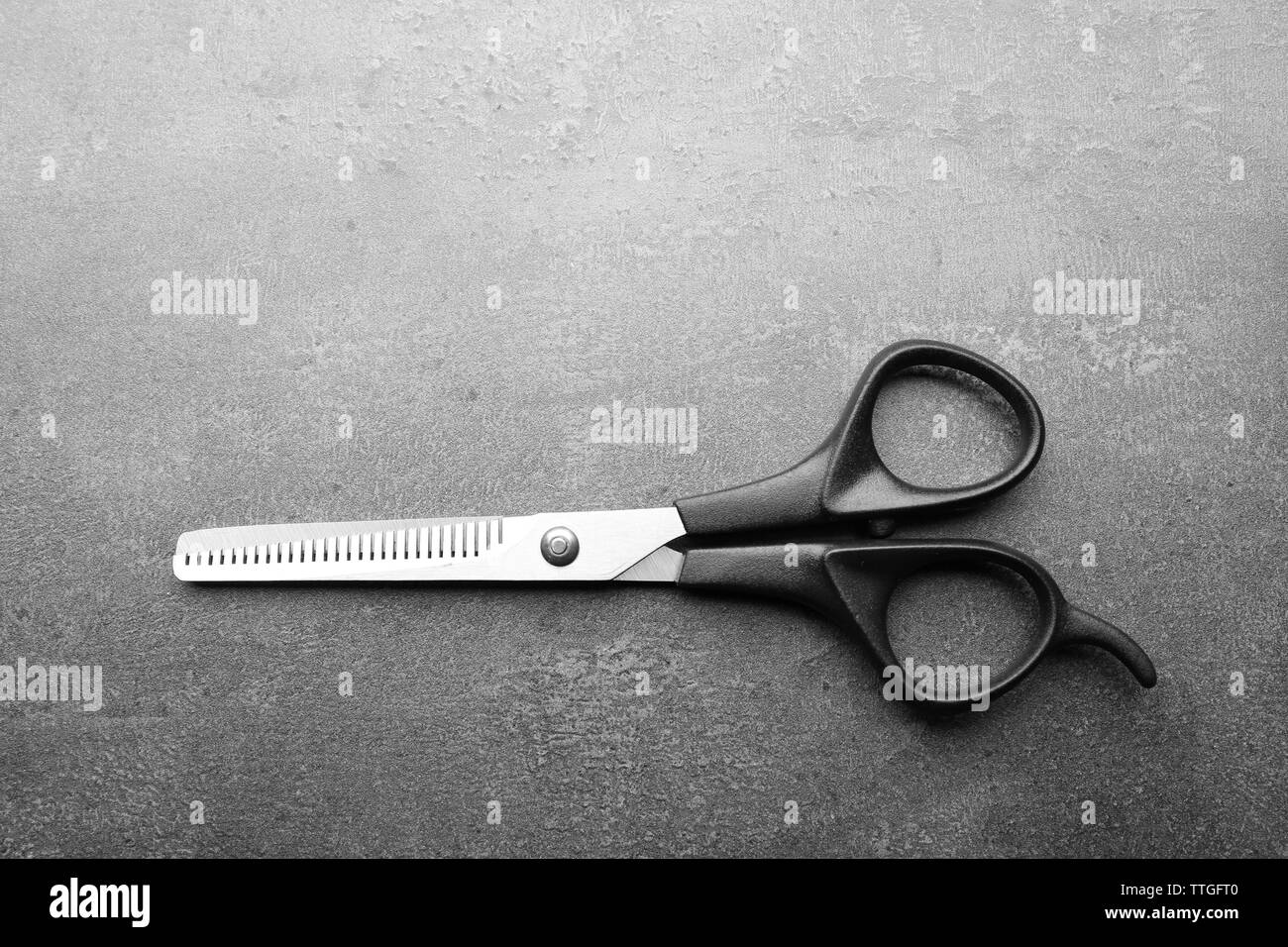 Professional scissors with black handles on a dark grey surface with ...