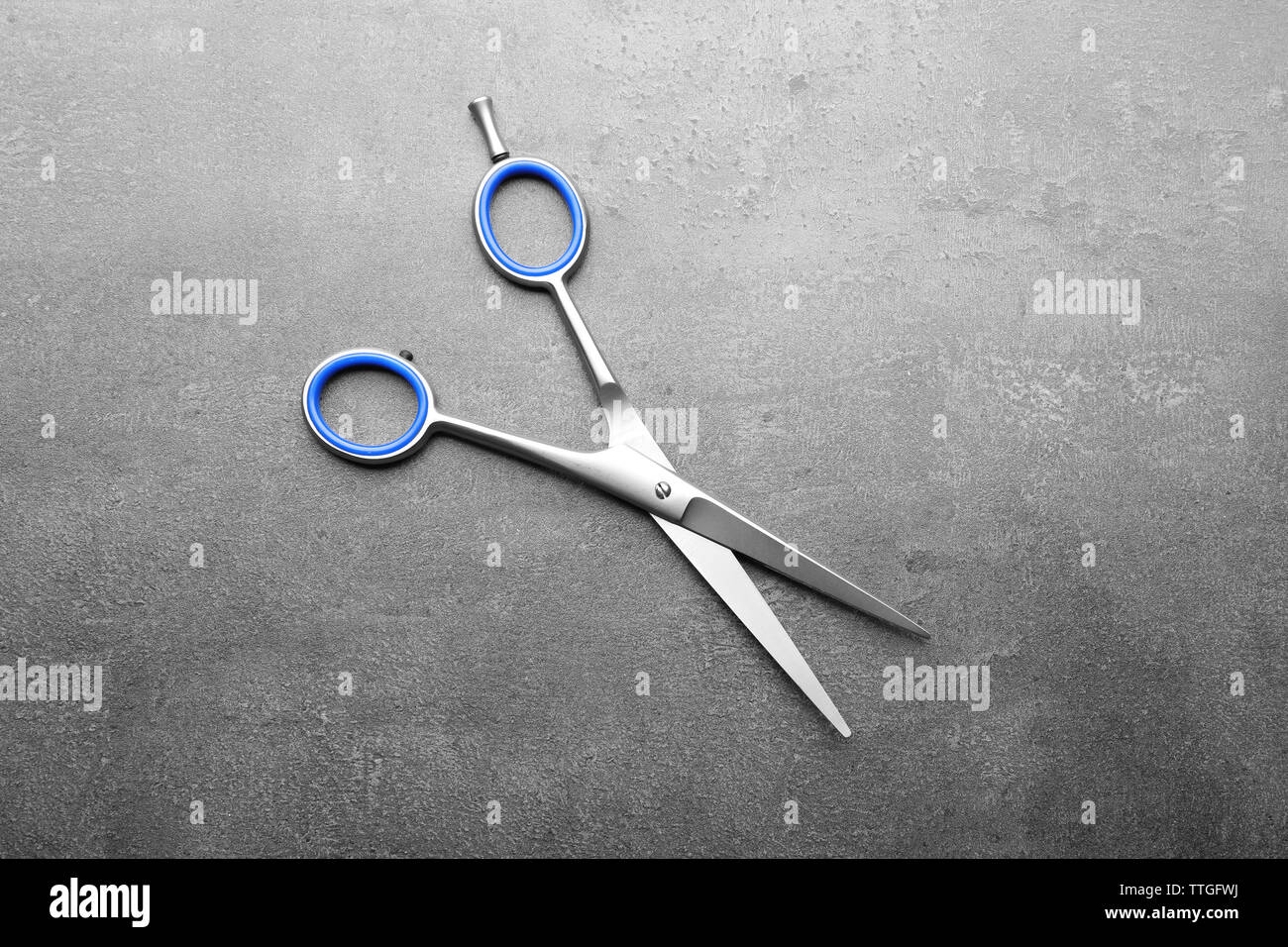 Professional metal scissors with blue-colored handle on a dark grey ...