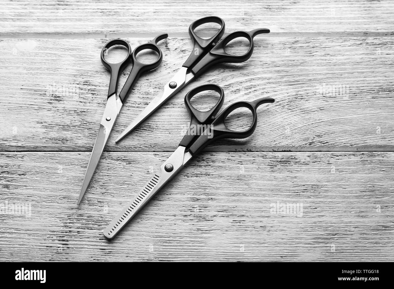 Three professional metal scissors with black handles lying beside each ...
