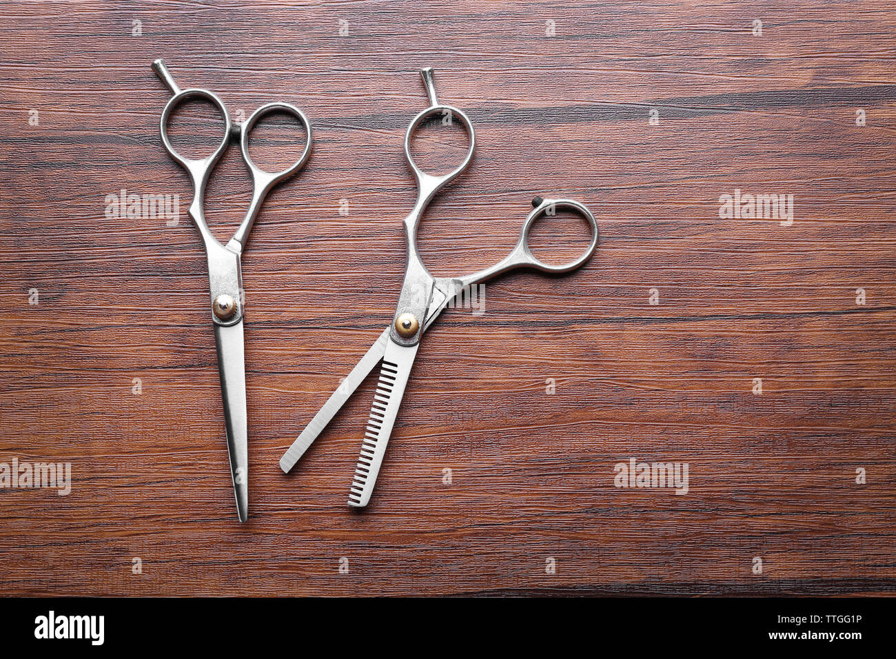 Two professional metal scissors lying on the wooden table, top view ...