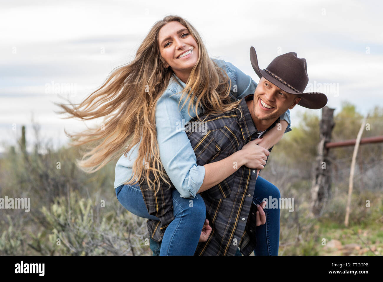 Western wear young couple giving piggy back ride on ranch Stock Photo ...