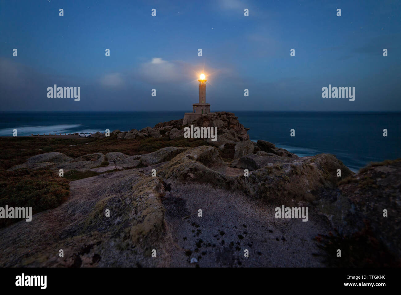 Illuminated Punta Nariga Lighthouse at coastline against sea and sky ...