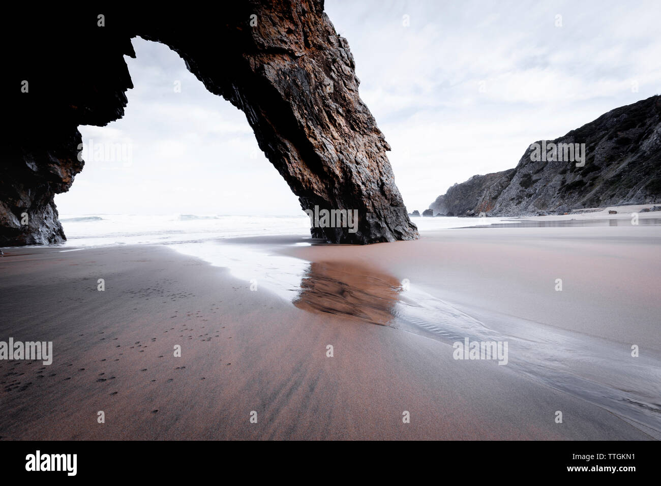 Scenic view of rocky arch on shore at Adraga beach Stock Photo - Alamy