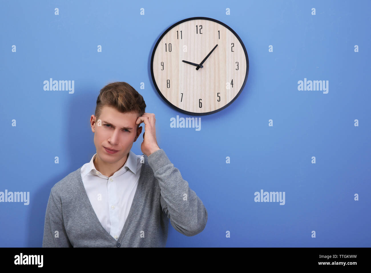 Young handsome man and clock on blue wall Stock Photo - Alamy