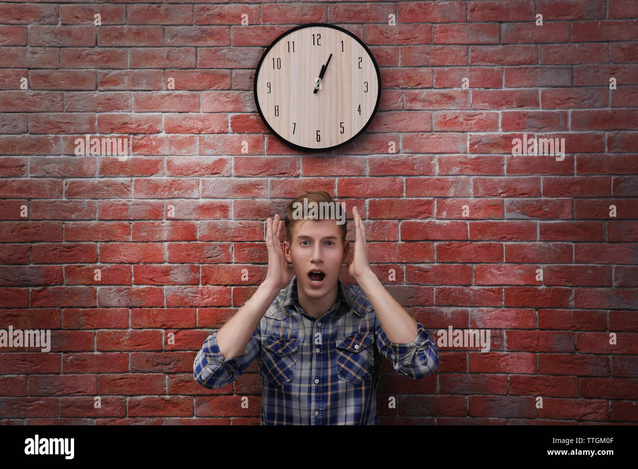 Young handsome man and clock on brick wall Stock Photo - Alamy