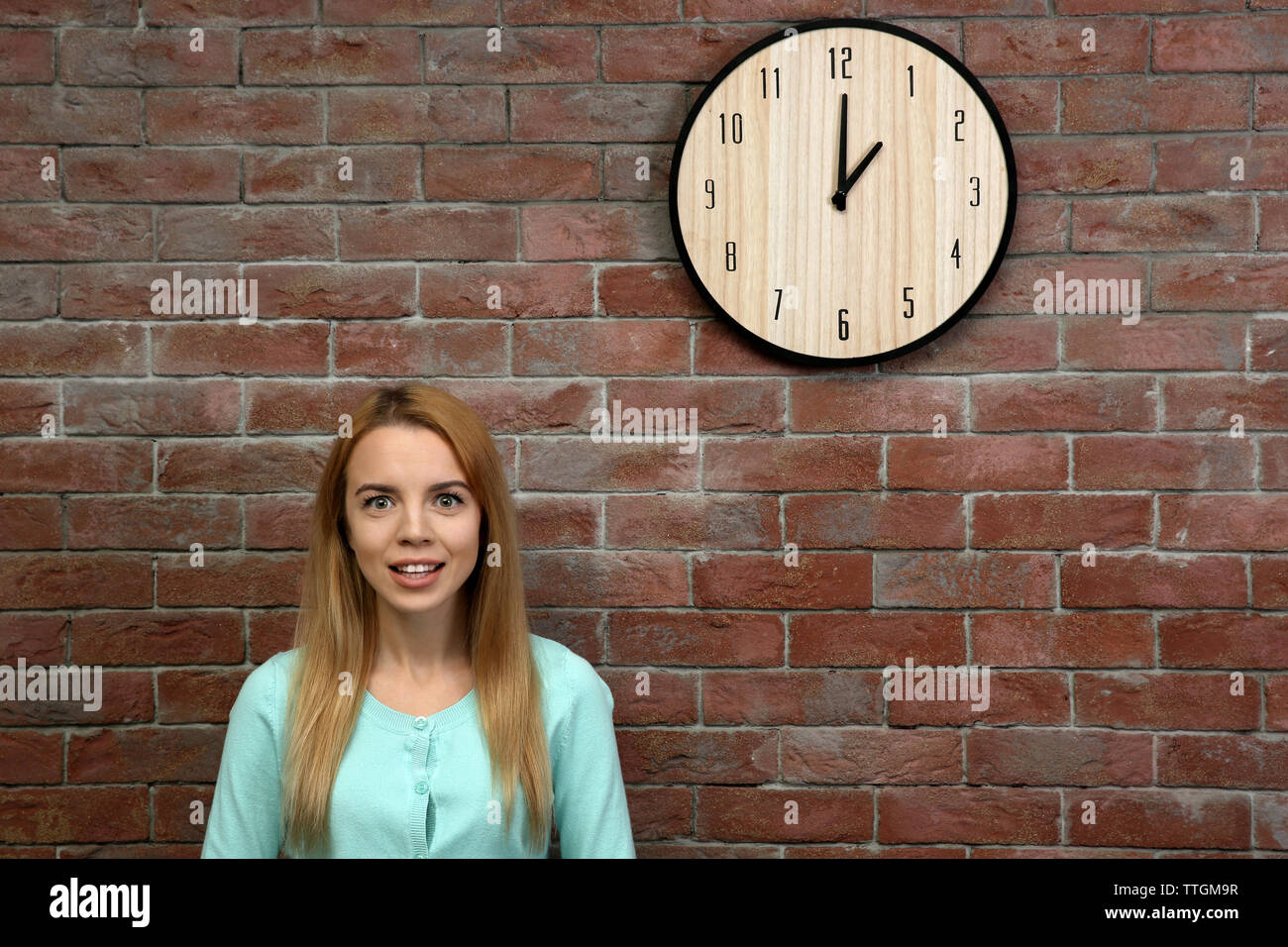 Young beautiful woman and clock on brick wall Stock Photo - Alamy