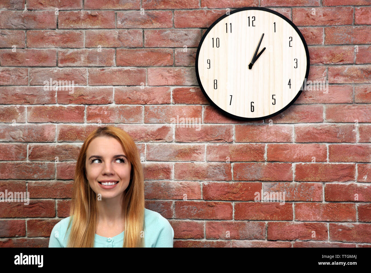 Young beautiful woman and clock on brick wall Stock Photo - Alamy