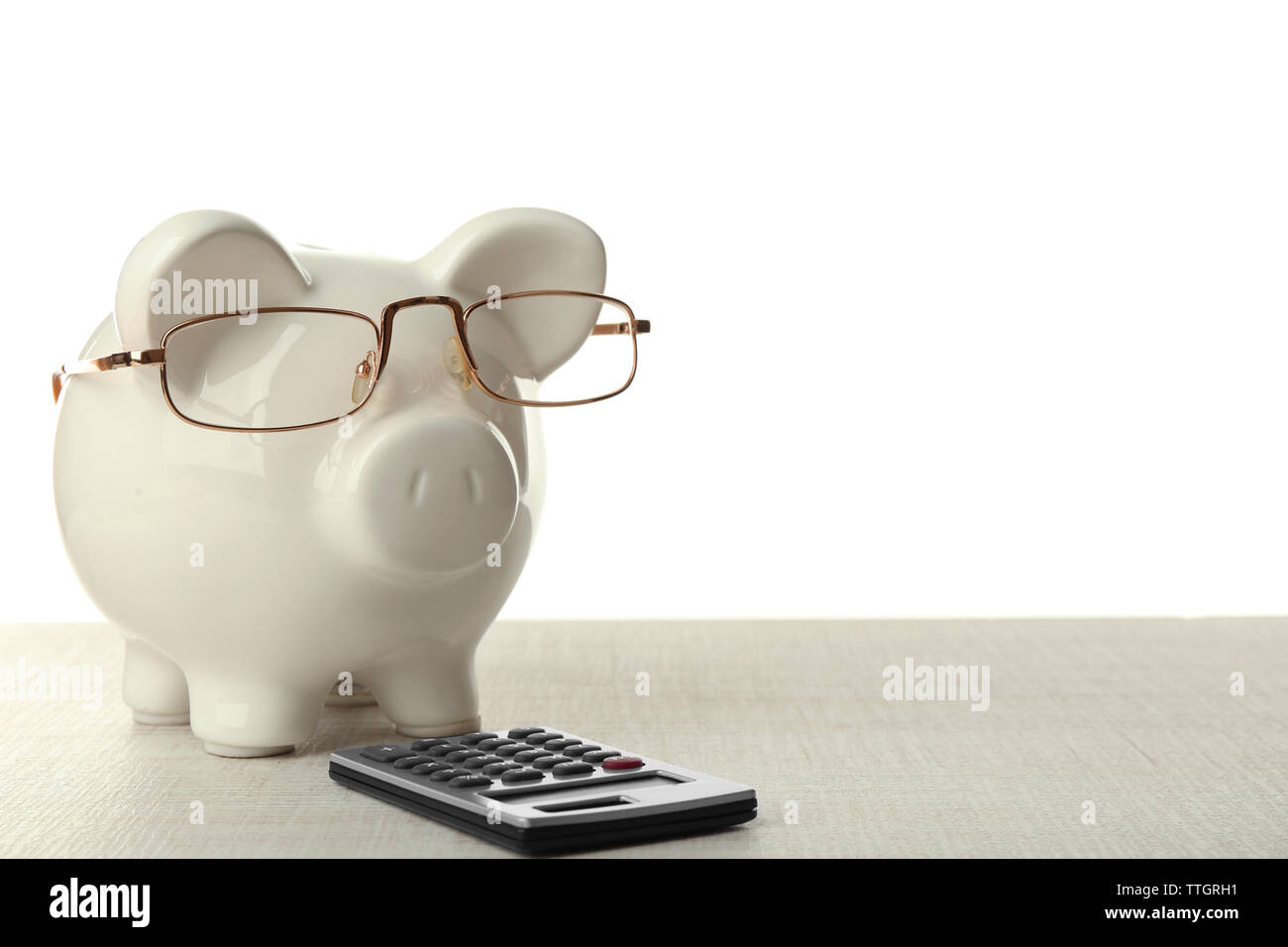 Piggy bank with glasses and calculator on white background Stock Photo ...