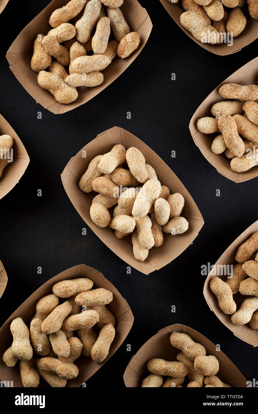 Peanuts with shell in disposable cardboard boxes on a black table Stock ...