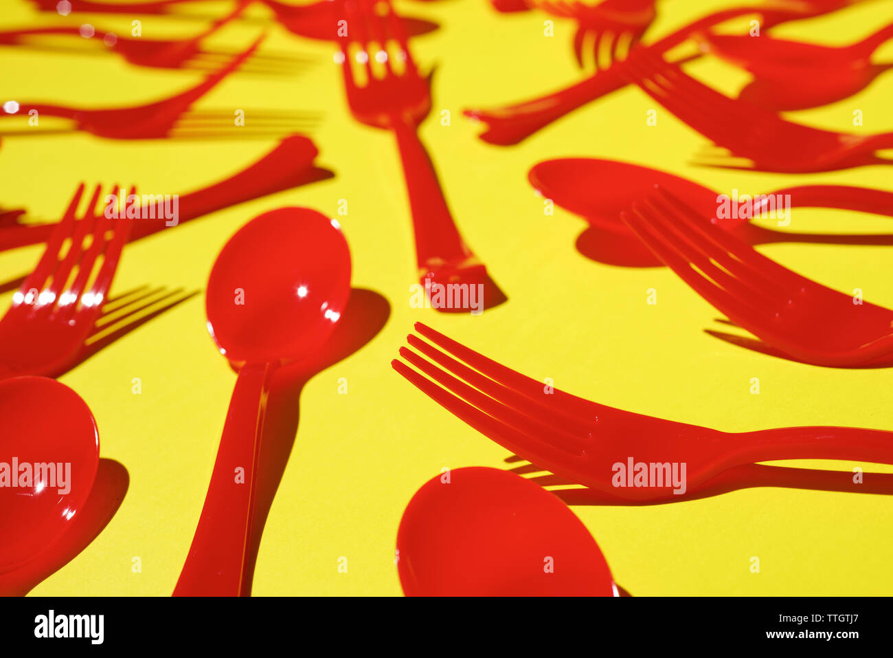 Red disposable plastic cutlery on a yellow table Stock Photo - Alamy
