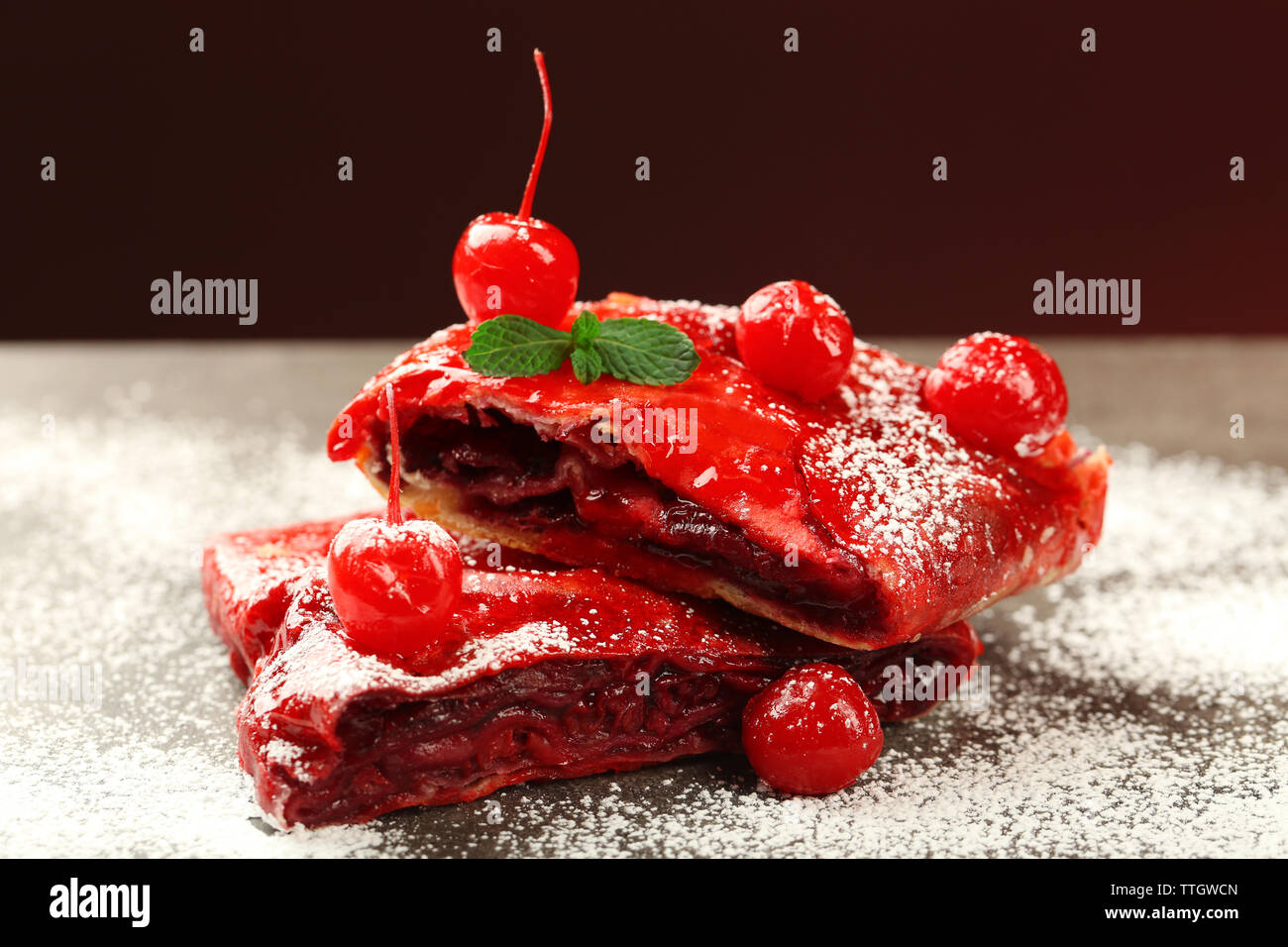 Powdered cherry strudel with mint on dark red background Stock Photo ...