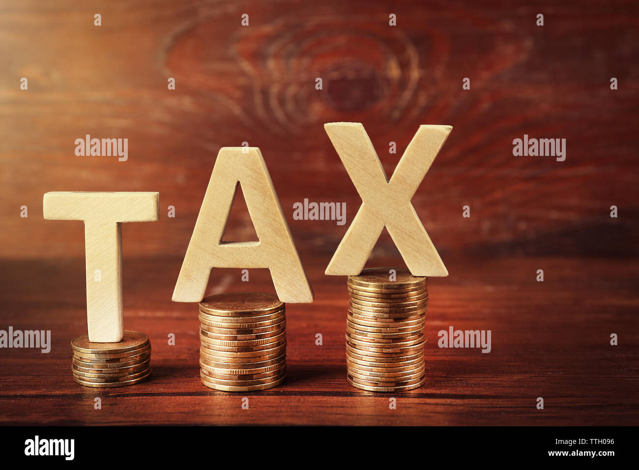 Word tax with stacked coins on wooden background Stock Photo - Alamy