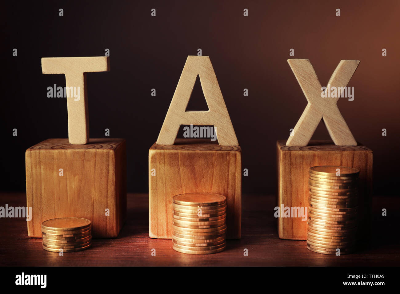 Word tax with stacked coins on dark background Stock Photo - Alamy