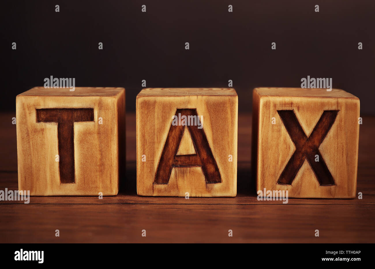 Word TAX written on wooden cubes on dark background Stock Photo - Alamy