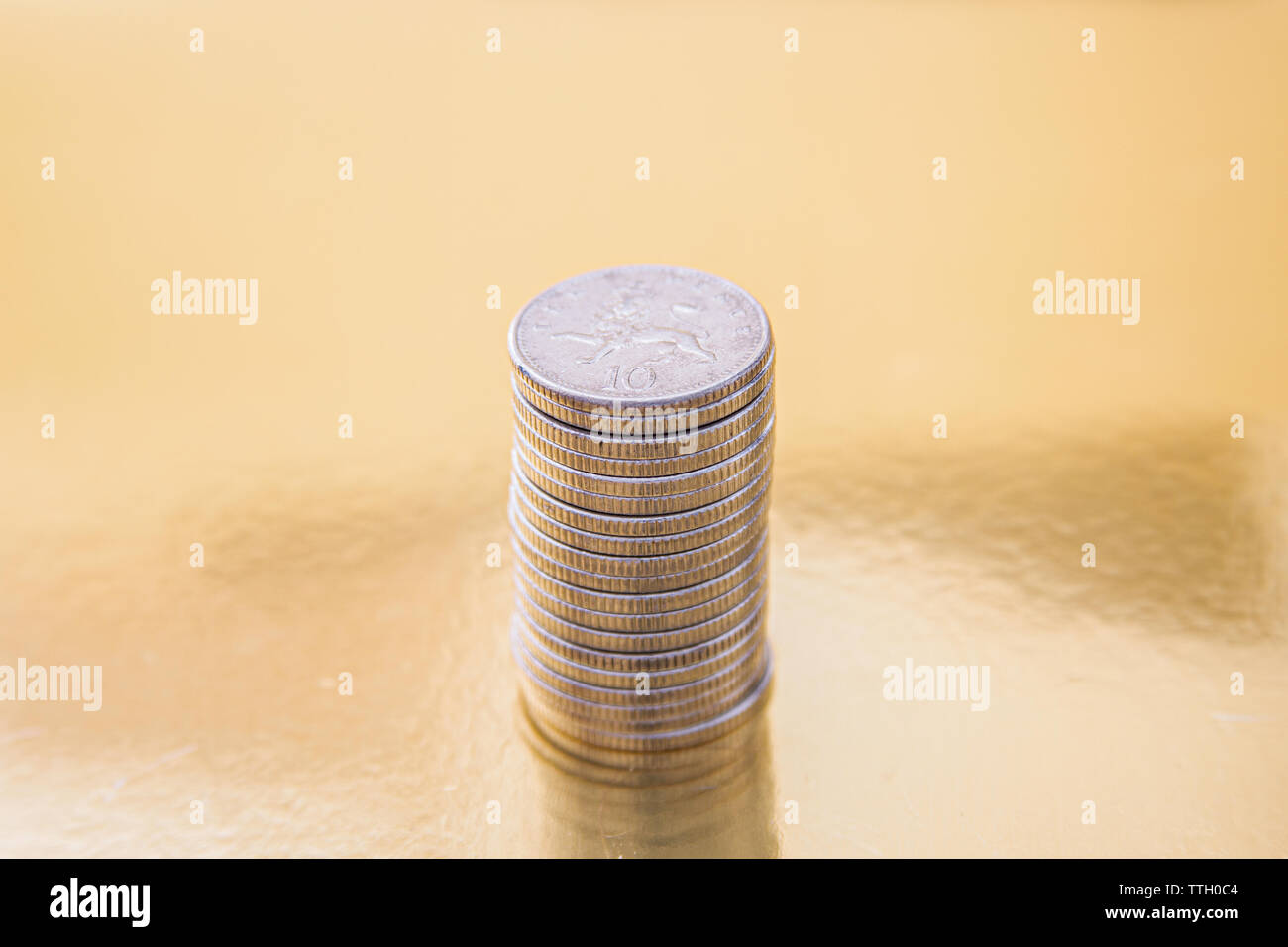 10p pieces. A stack of British coins on a gold background Stock Photo ...