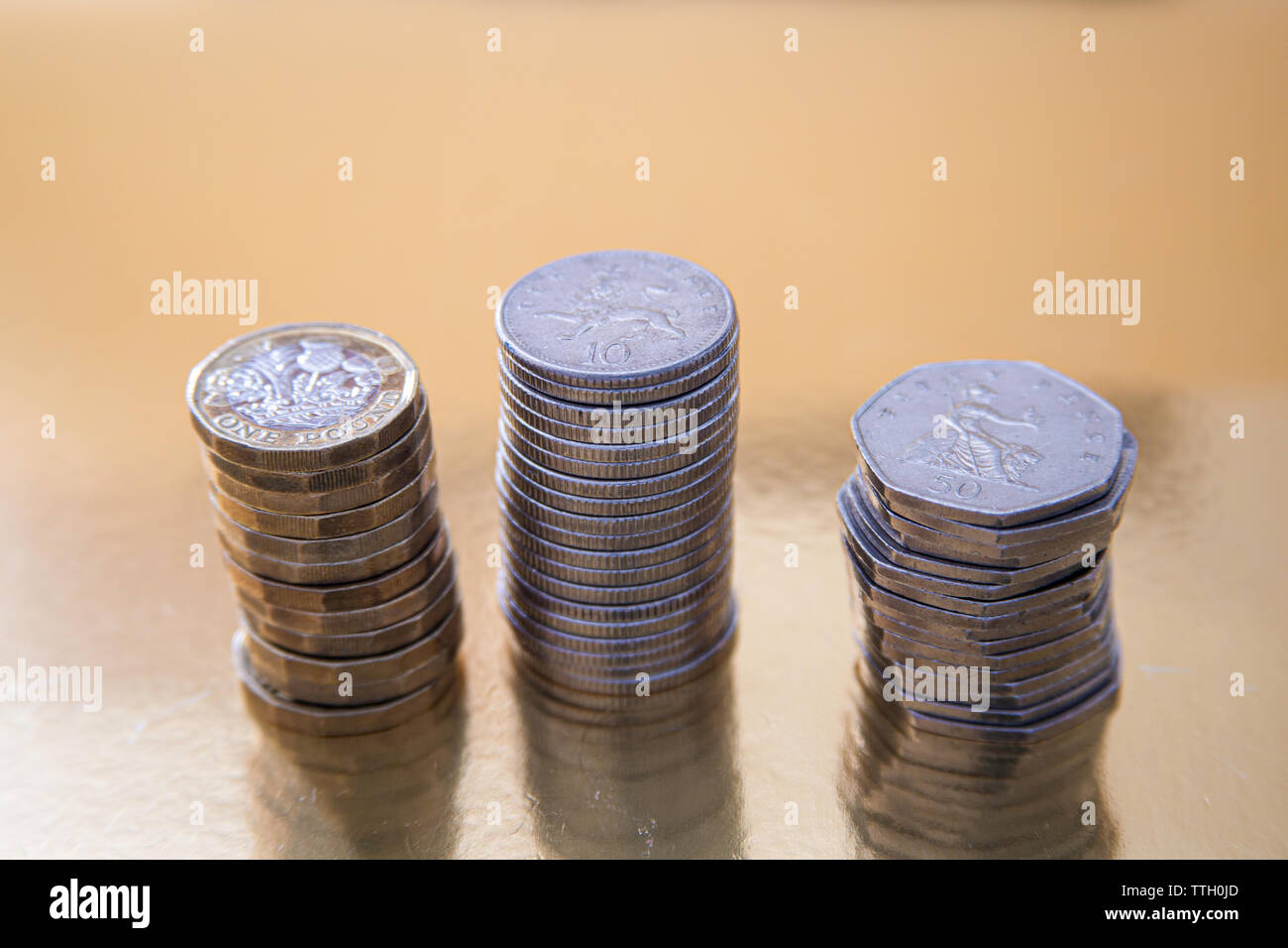 Three stacks of gold coins stacked up on a gold background Stock Photo ...