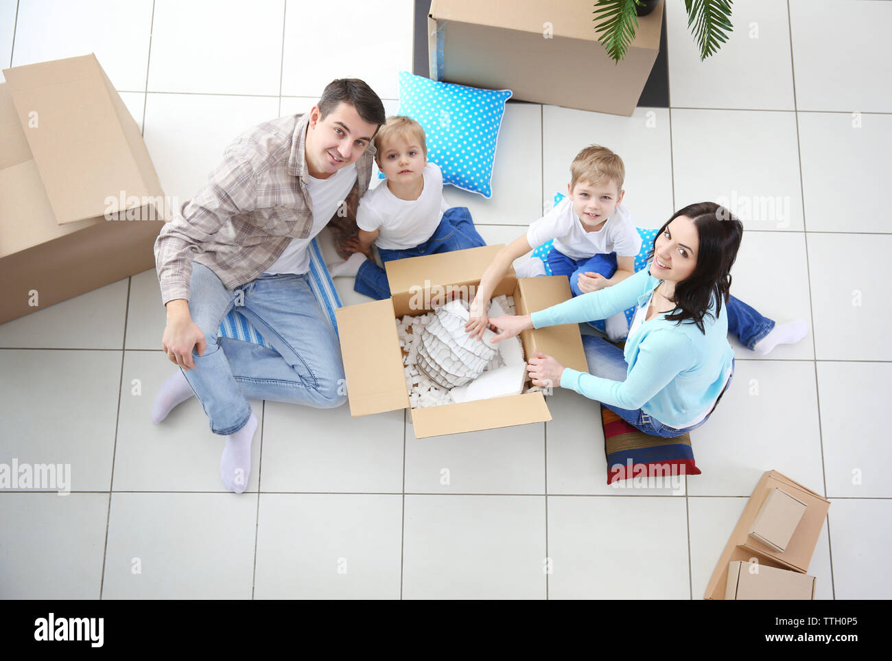 Moving concept. Happy family unpacking boxes in new house, top view ...