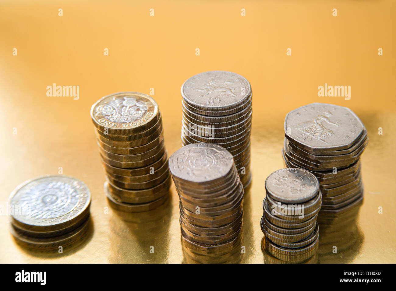 Various British coins in stacks on a gold background Stock Photo - Alamy