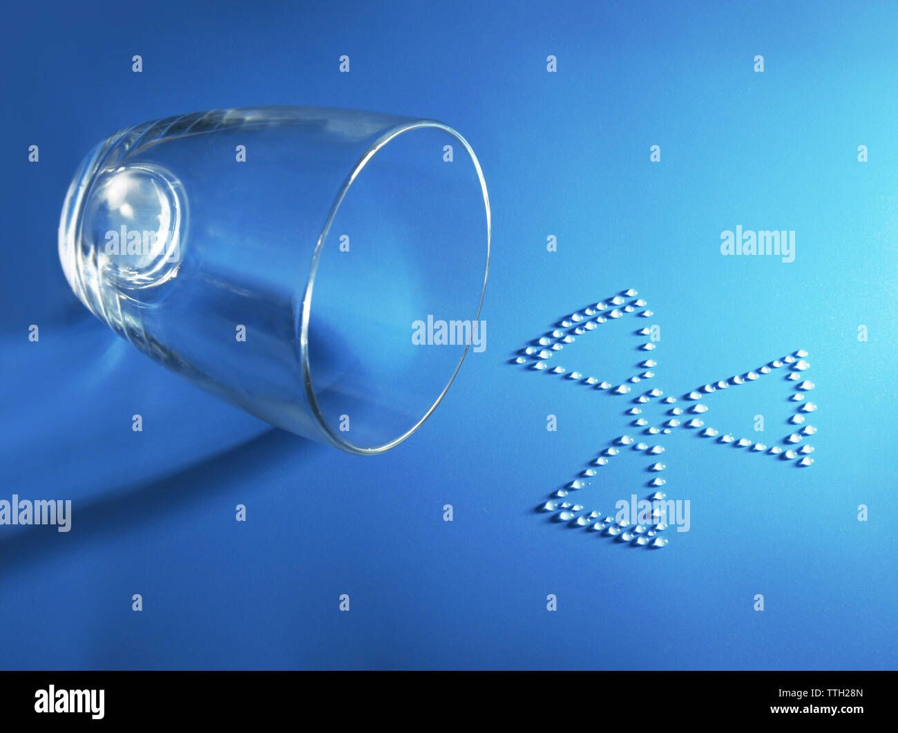 Radiation sign made of water drops and empty glass on blue background ...