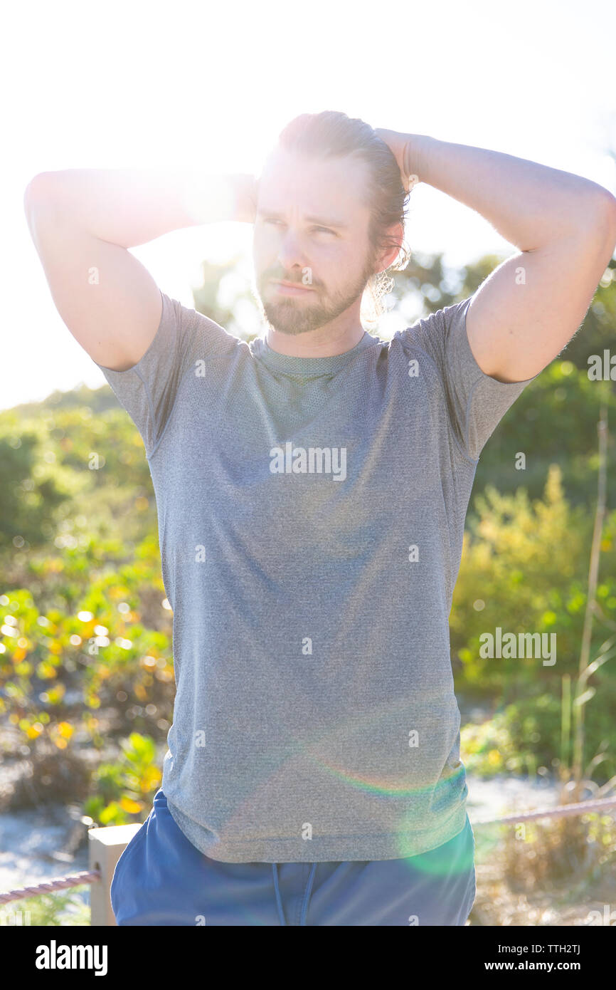 Portrait of a fit man running his hands through his hair while outside ...