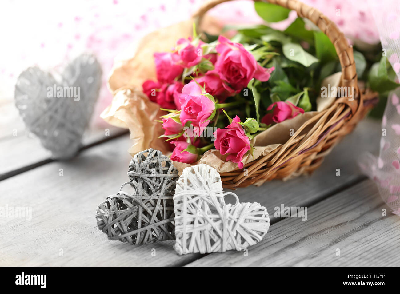 Pink roses in a wicker basket and decorative hearts on a white table, close up Stock Photo - Alamy