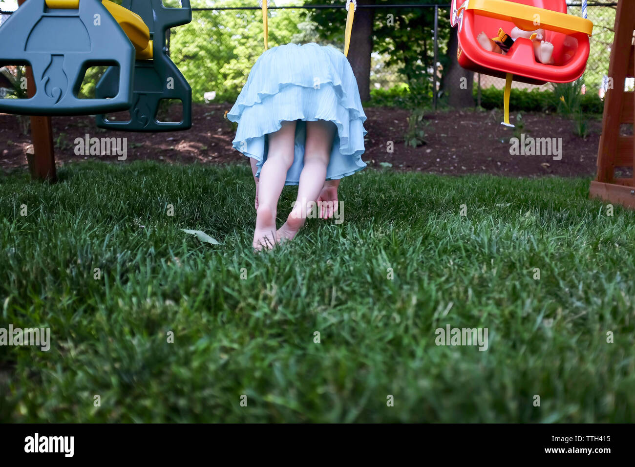 Rear view of playful girl on swing at playground Stock Photo - Alamy