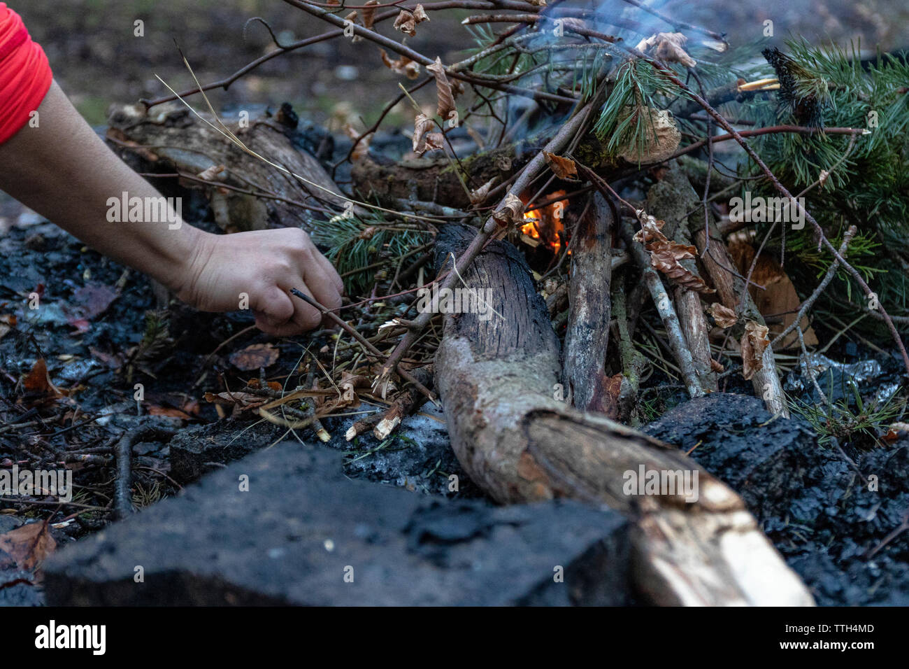 Woman starting a bonfire at a fireplace in the forest in autumn Stock ...